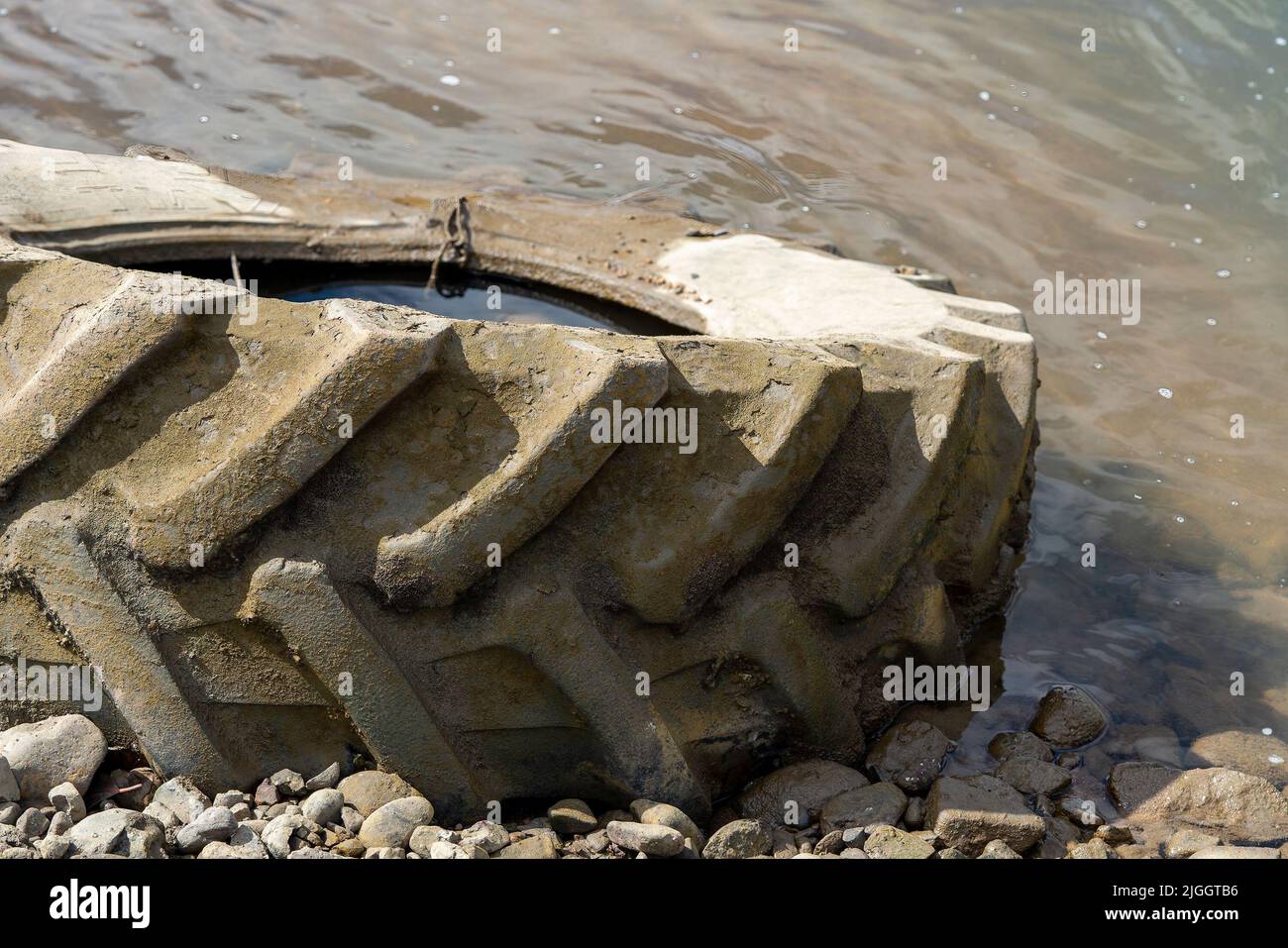 Old rubber car tyre dumped in a river at low tide Stock Photo - Alamy