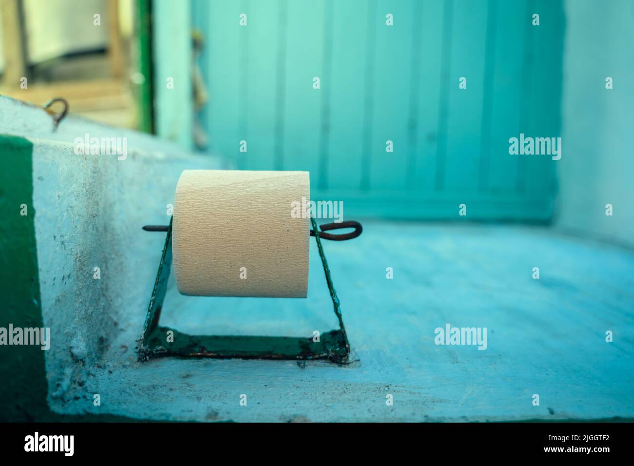 A roll of the cheapest single ply toilet paper on a toilet paper holder ...