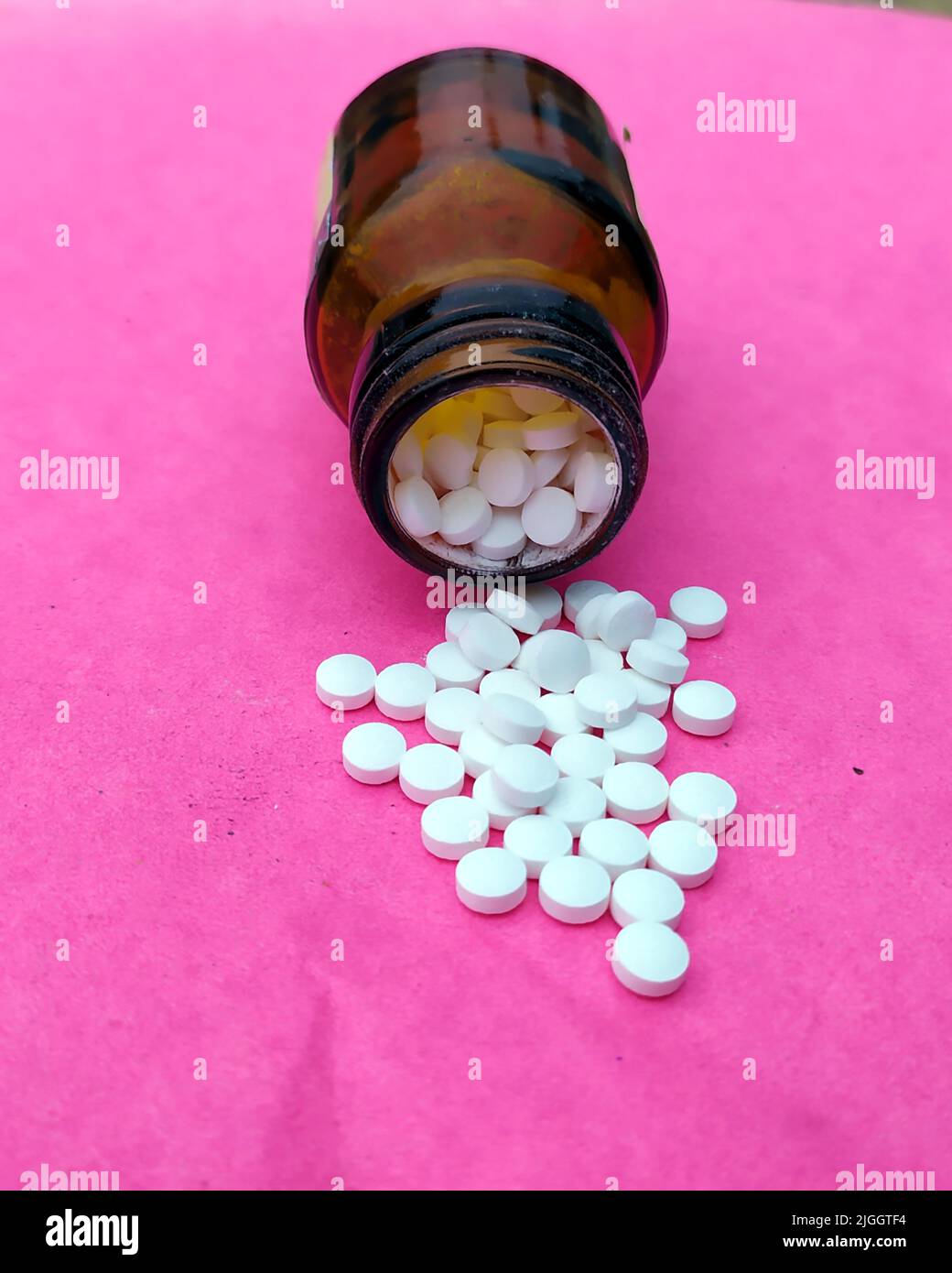 white,medician tablet out of bottle at pink background Stock Photo - Alamy