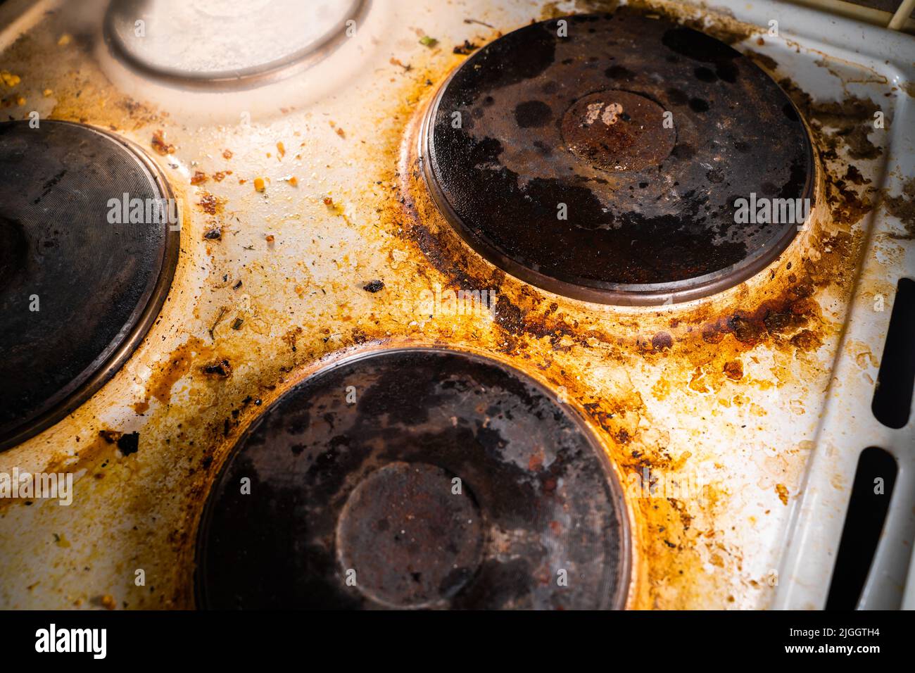 Very heavily soiled old kitchen electric stove in burnt brown soot and ...