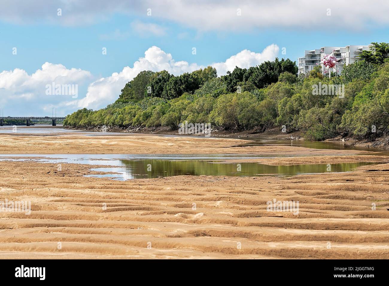 A river running through a city at low tide with sand banks showing ...