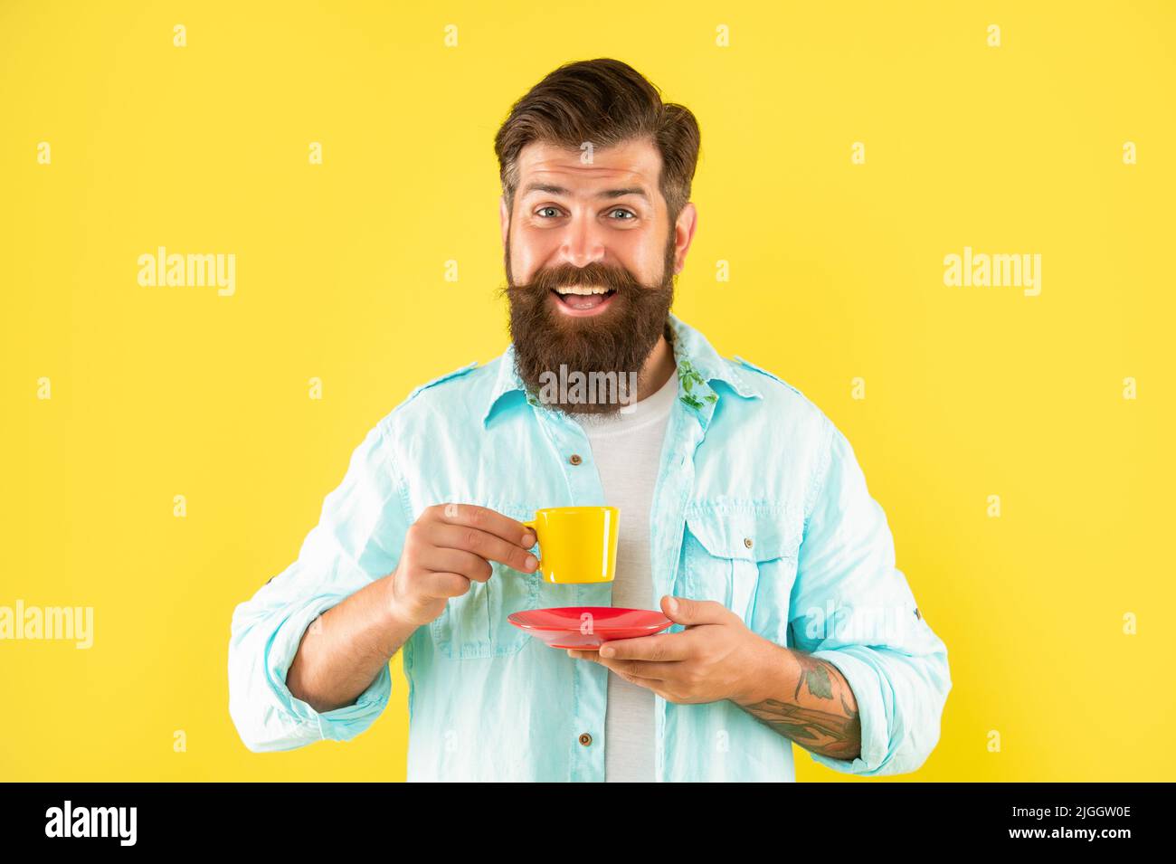 cheerful unshaven man in shirt with coffee on yellow background ...