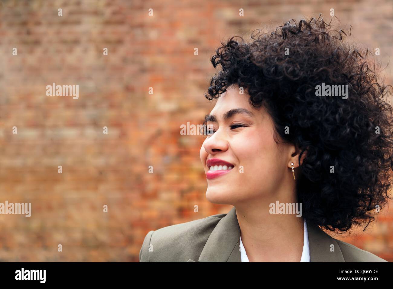 portrait of a young woman with curly hair smiling Stock Photo - Alamy