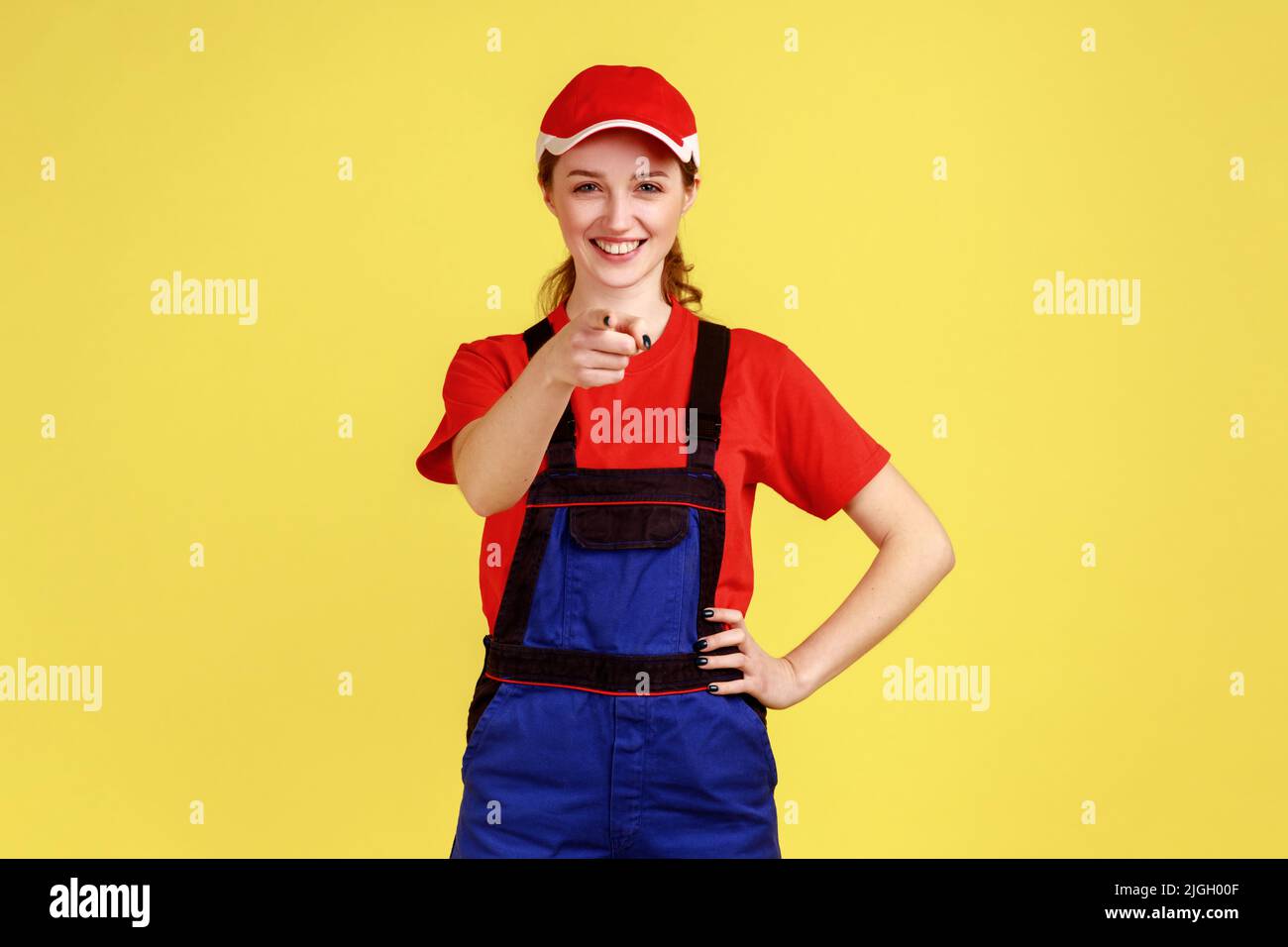 Portrait of smiling positive worker woman standing with hand on hip and ...