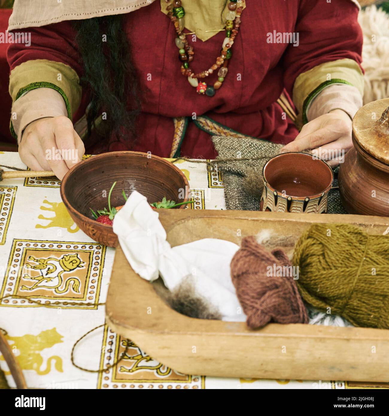 A woman in ancient Byzantine clothing makes yarn and sews from vintage ...