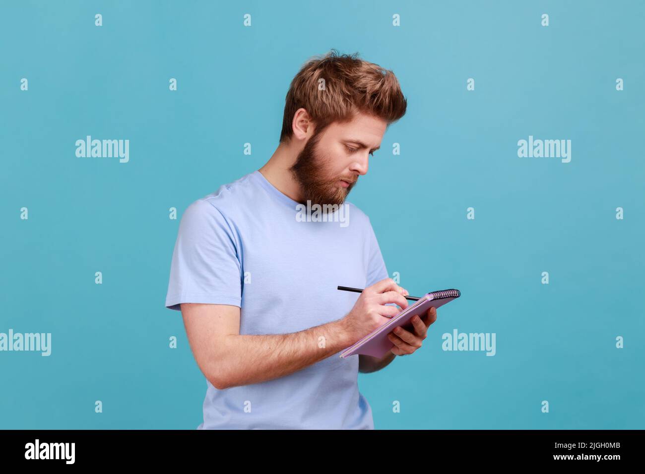 Portrait of bearded man making notes in paper notebook, writing ...