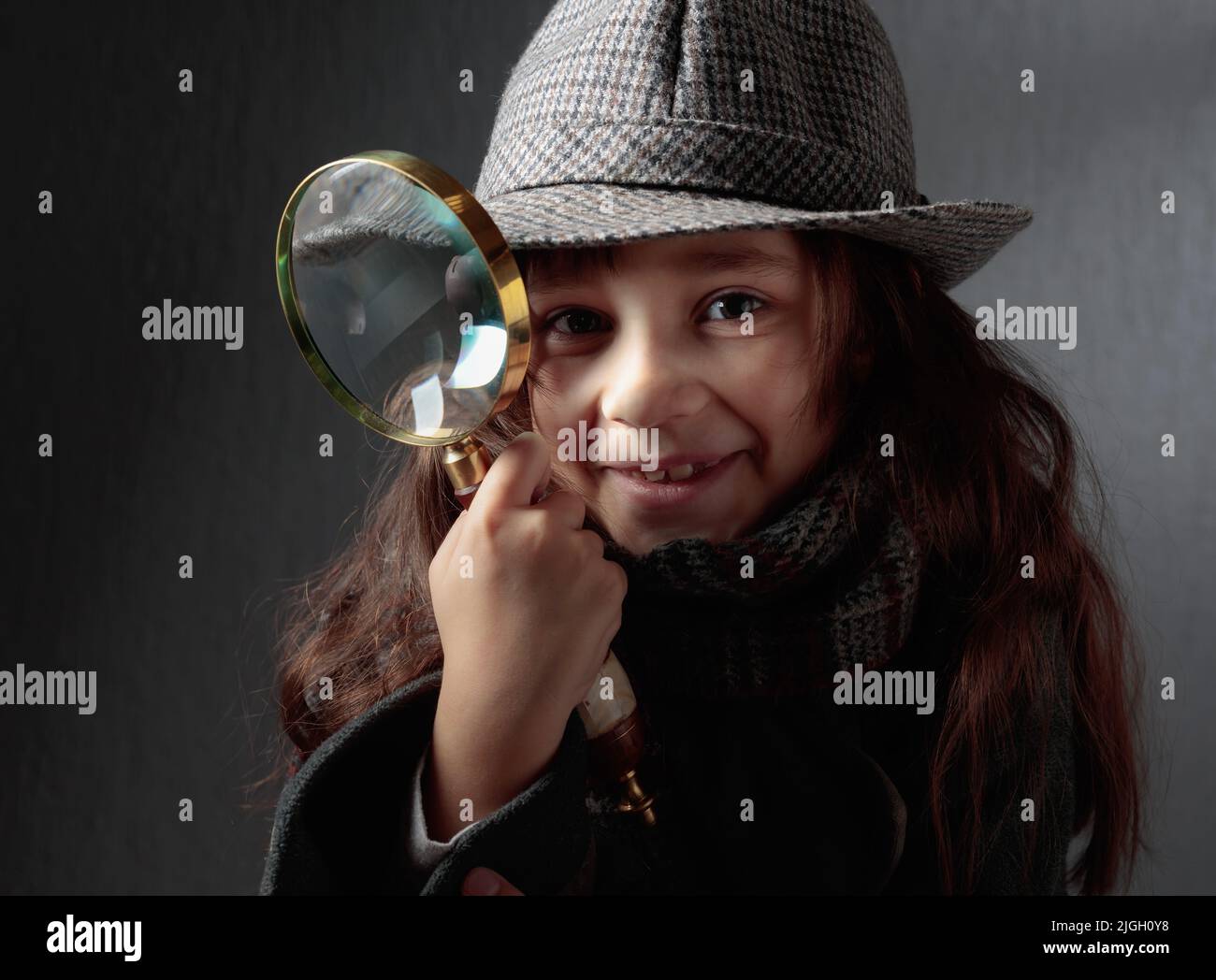 Cute little detective with a magnifying glass. A little girl in a hat ...