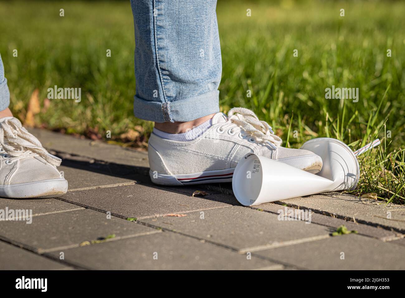 foot in shoes steps on a paper cup with a straw. High quality photo ...