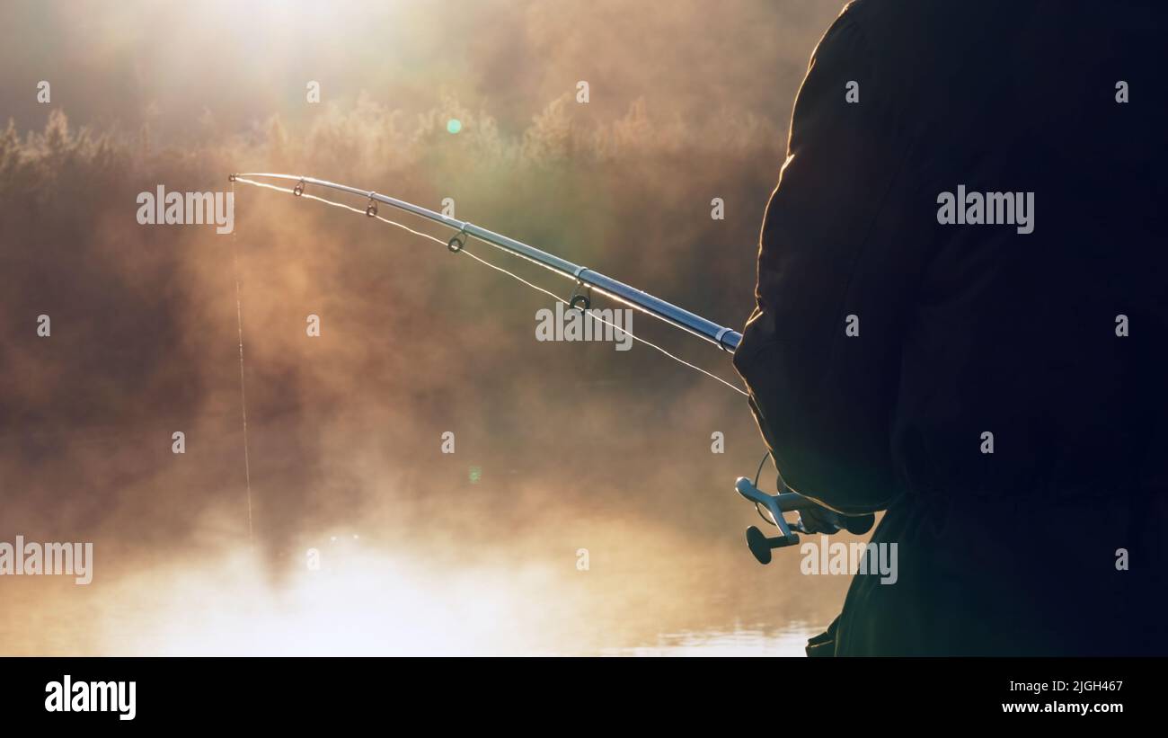 A back shot of human holding fishing rod in the dusty sunlight Stock ...