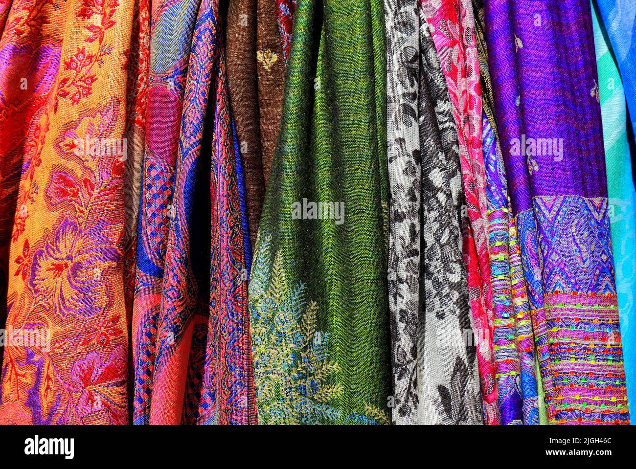 Colorful shawls, scarves on display in shop, background fabric texture ...