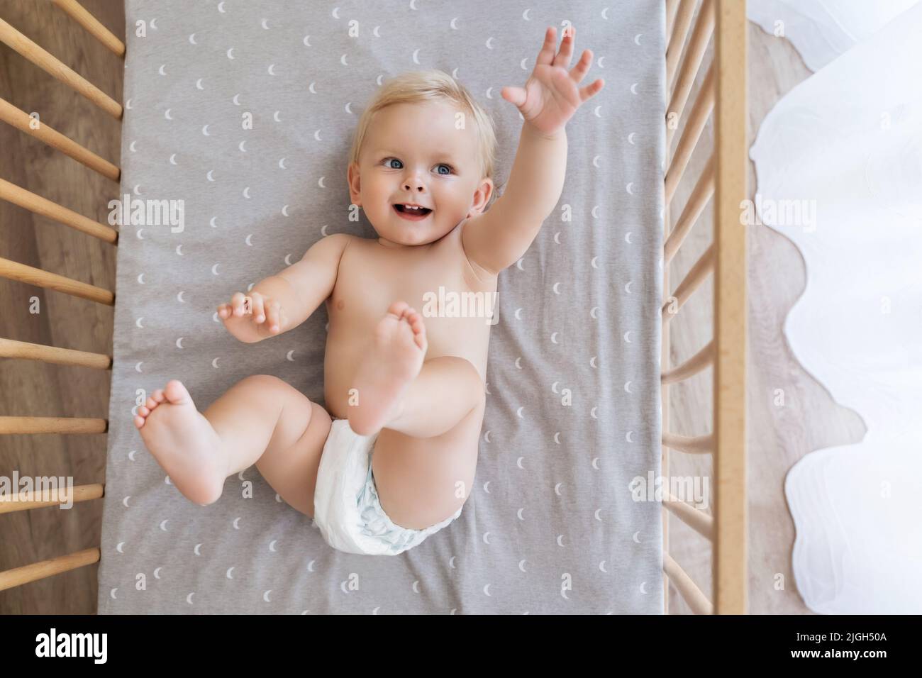 Upper view of little playful baby boy in diaper lying on his back ...