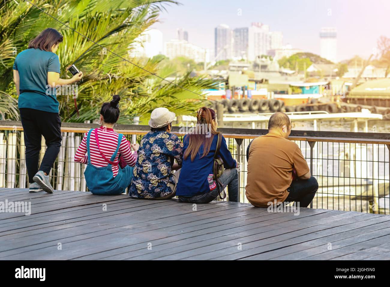 Back view of Asian friends relaxing and chilling at riverside. Relax ...