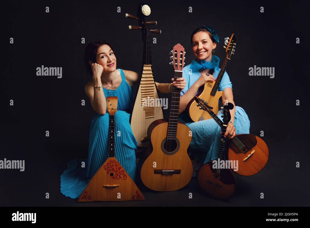 Women musicians in blue dresses with musical instruments on a black ...