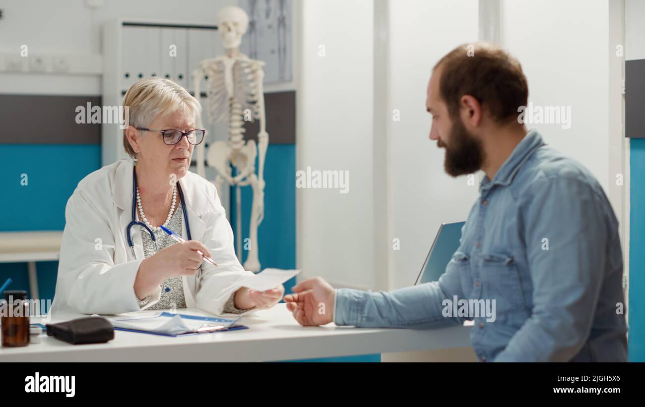 Senior medic and sick patient attending health checkup visit in cabinet ...