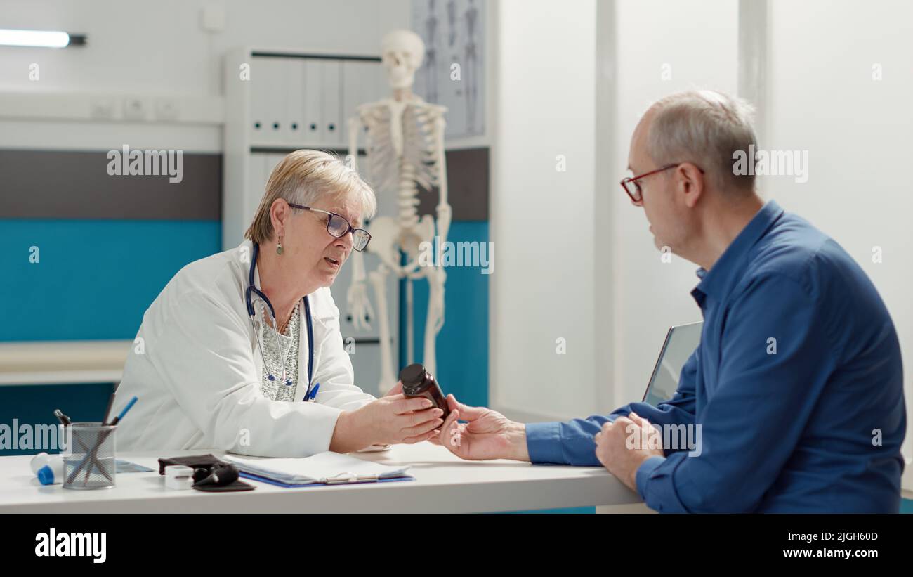 Medical specialist explaining bottle of medication and pills to old man ...