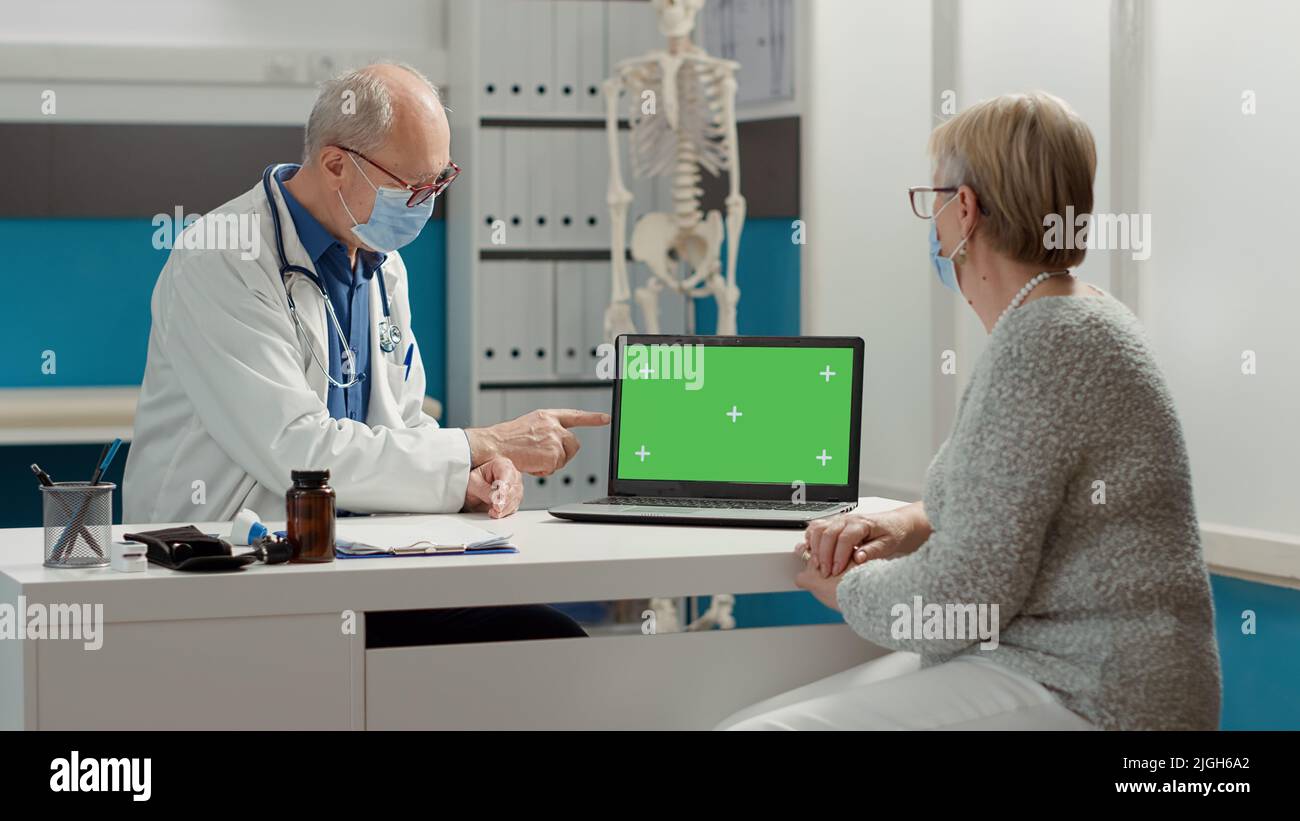 Medical specialist showing greenscreen on laptop to woman at checkup in ...
