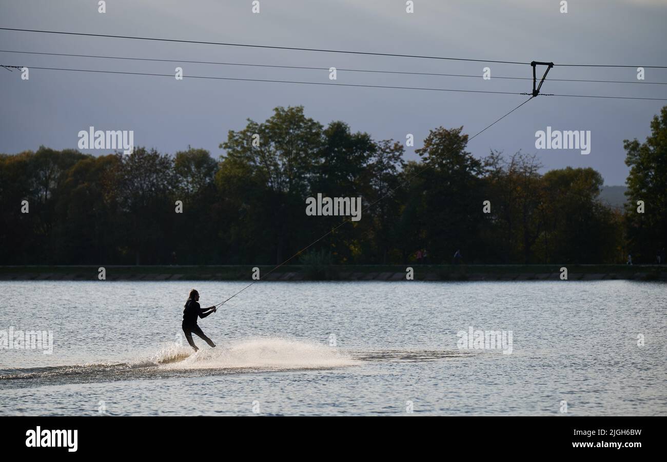 Silhouette of wakeboarder surfing on lake. Athletic man surfer having ...