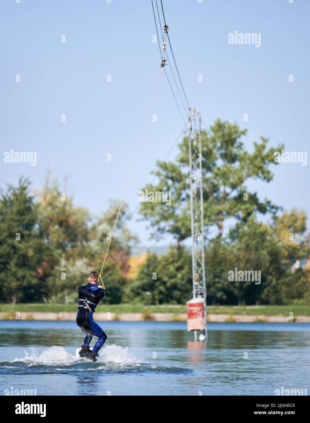 Back view of wakeboarder surfing on lake. Young surfer having fun ...