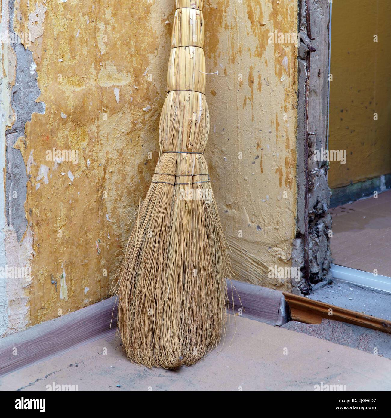 A straw broom stands in a corner against a shabby wall Stock Photo - Alamy