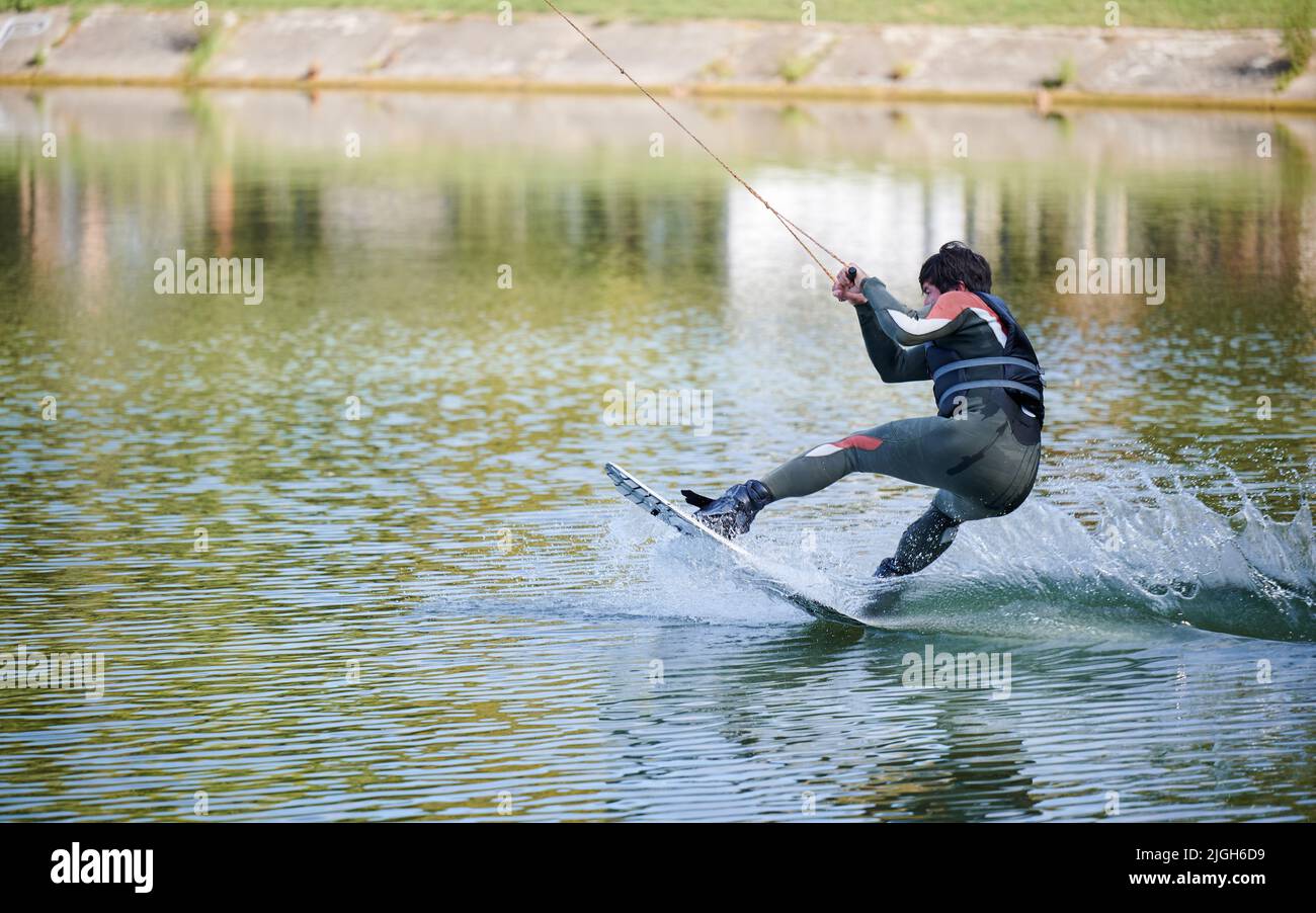 Wakeboarder surfing on lake. Young man surfer having fun wakeboarding ...