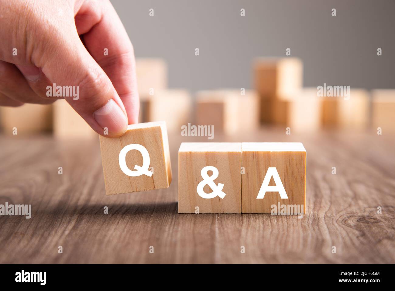 Hand holding Q and A word with wooden cube block. Questions and Answers ...