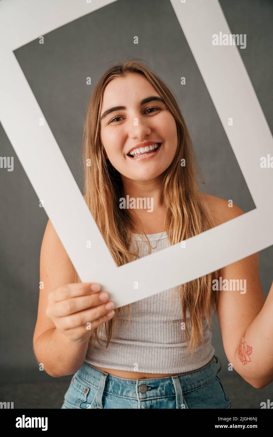 Close up Caucasian female smiling holding a frame to frame her face ...