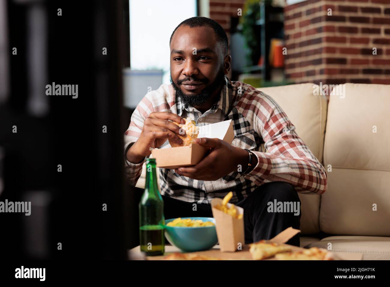 Casual person eating burger from takeaway delivery and watching movie ...