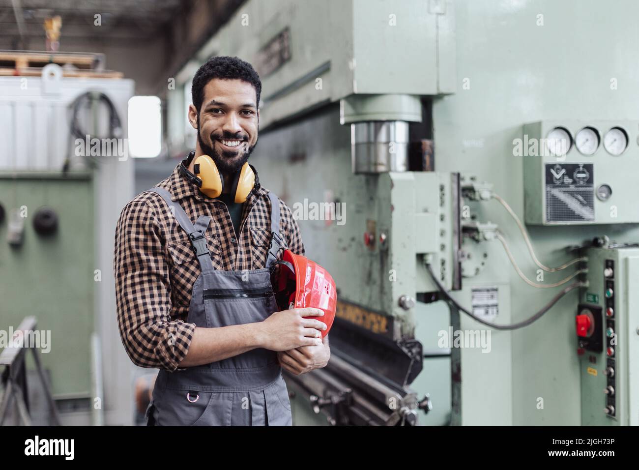 Heavy industry worker with safety headphones and hard hat in industrial ...