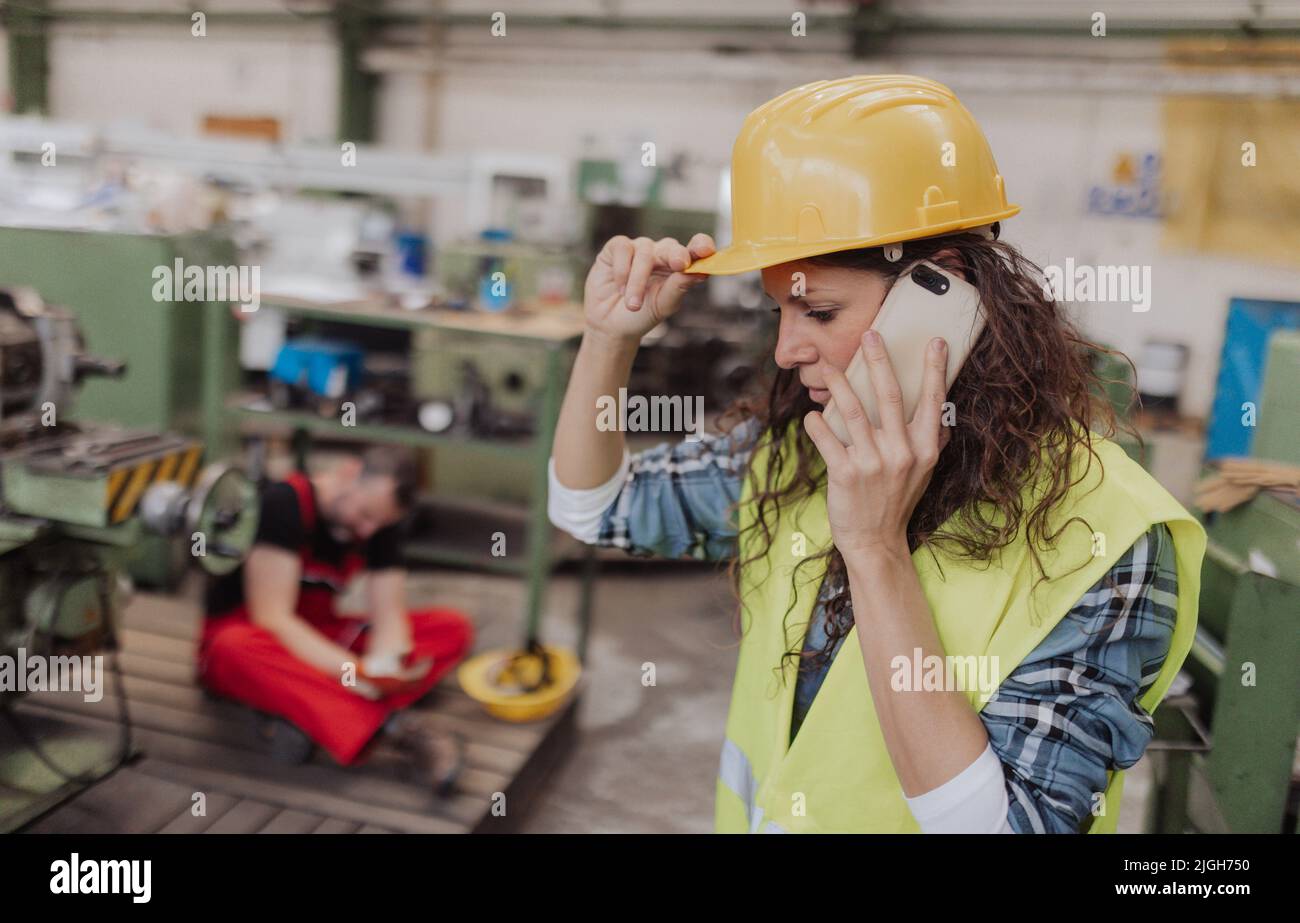 Woman is calling ambulance for her colleague after accident in factory ...