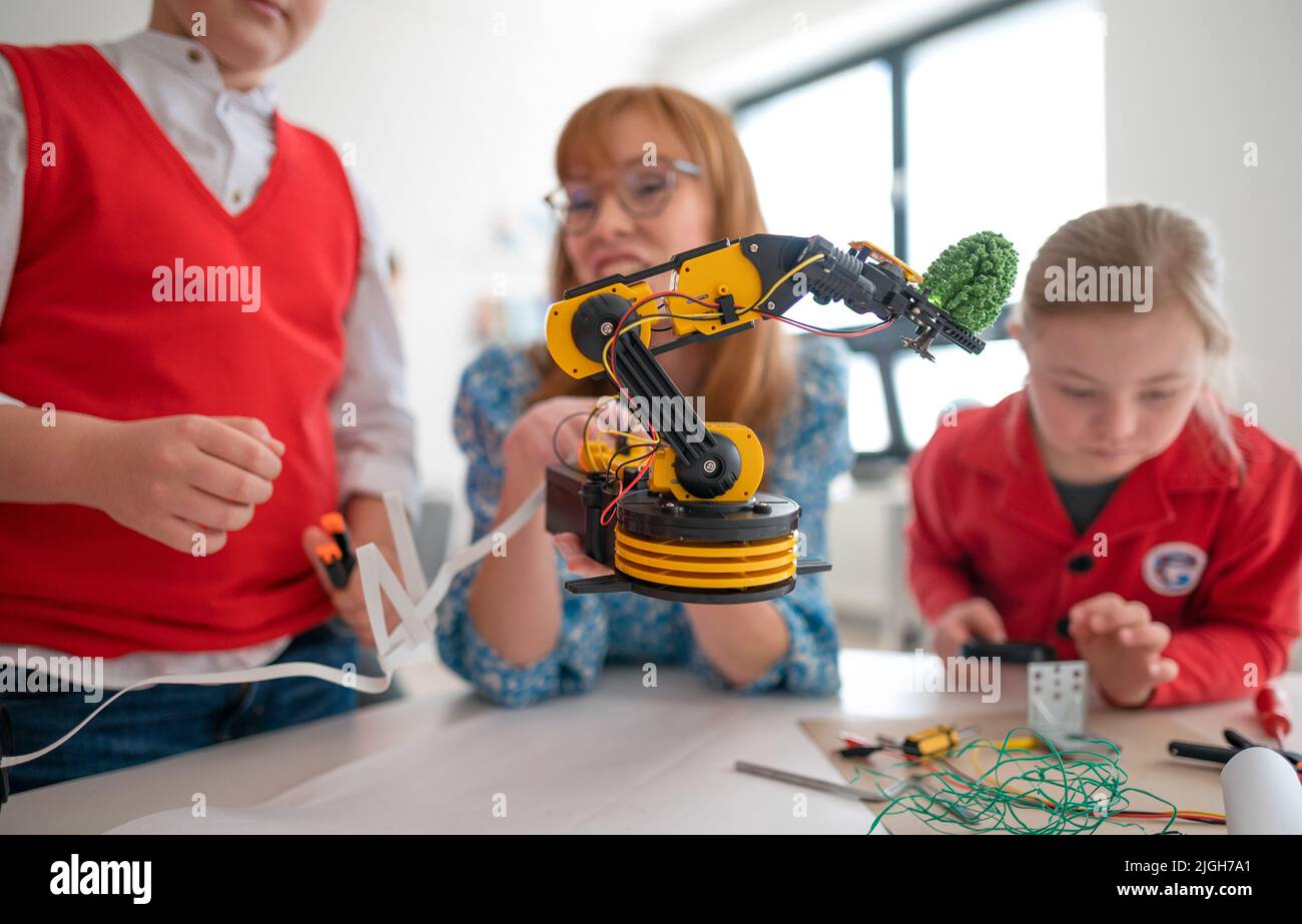 Group of kids with young science teacher programming electric toys and ...