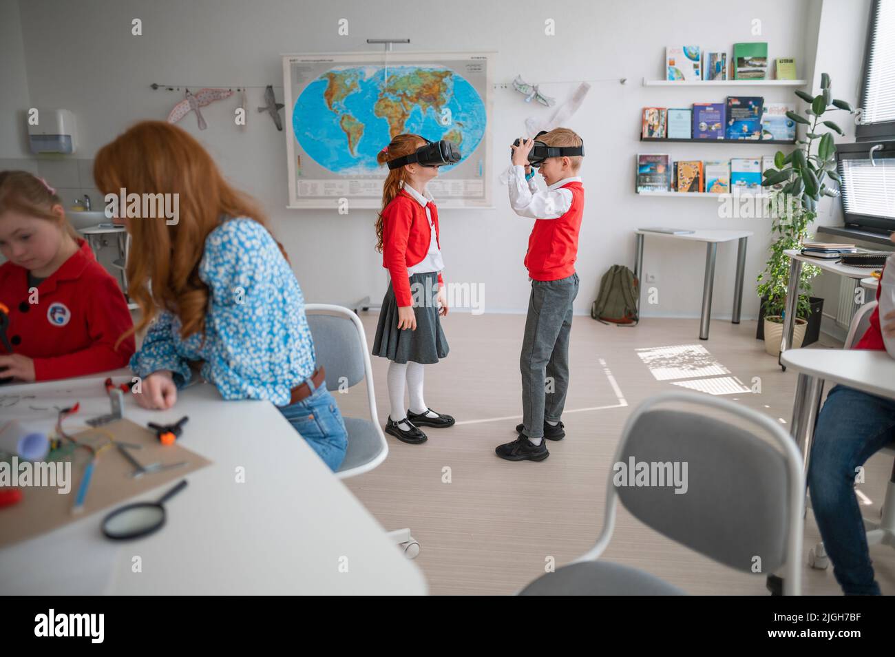Happy schoolchildren wearing virtual reality goggles at school in ...
