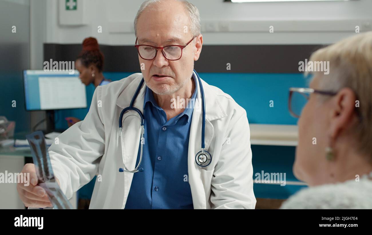 Medic and old patient analyzing bones radiography at checkup visit ...