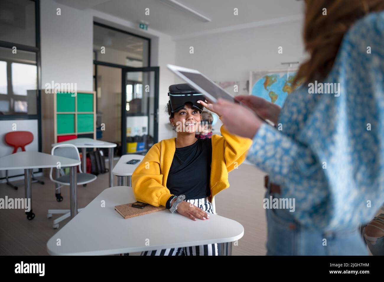 Young high school teacher giving lesson to students with VR goggles in ...