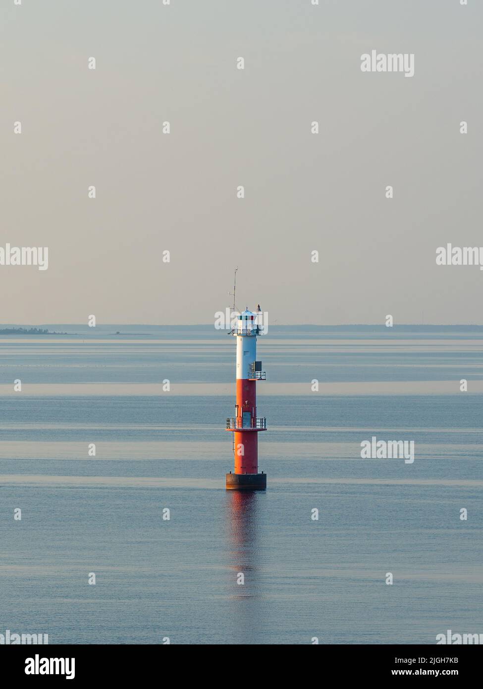 The vertical view of a lighthouse standing in the blue sea on a sunny ...