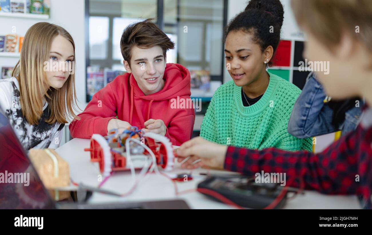 Group of high school students building and programming electric toys ...