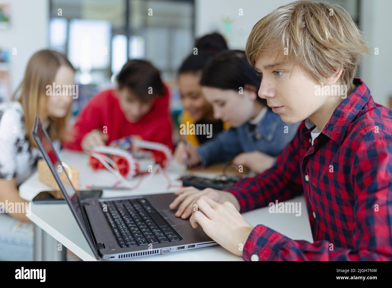 Group of high school students building and programming electric toys ...
