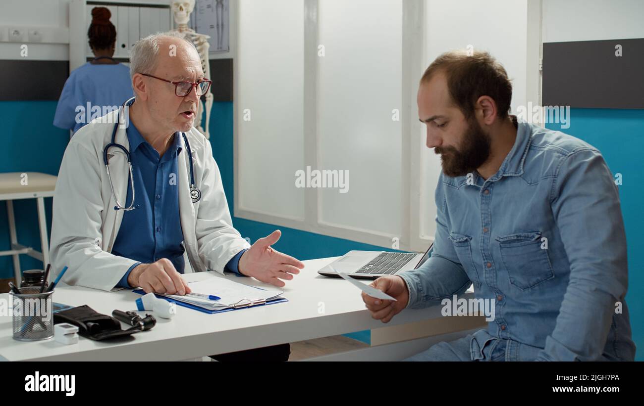 Male physician giving prescription paper to sick person at checkup ...