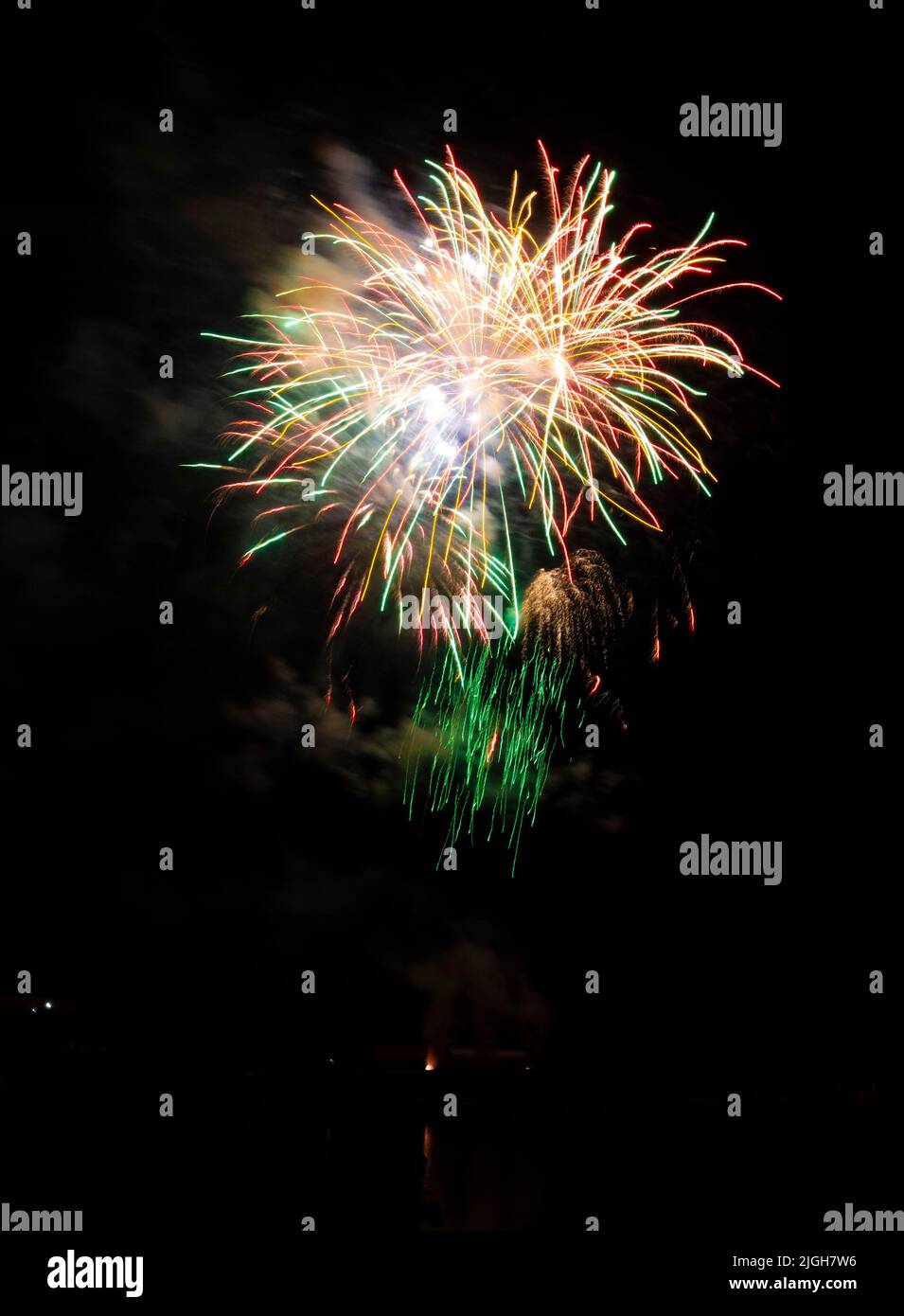 A vertical shot of exploding colorful fireworks in a dark night sky ...