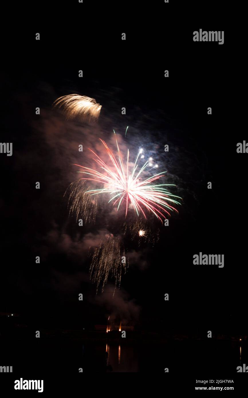 A vertical shot of exploding colorful fireworks in a dark night sky ...