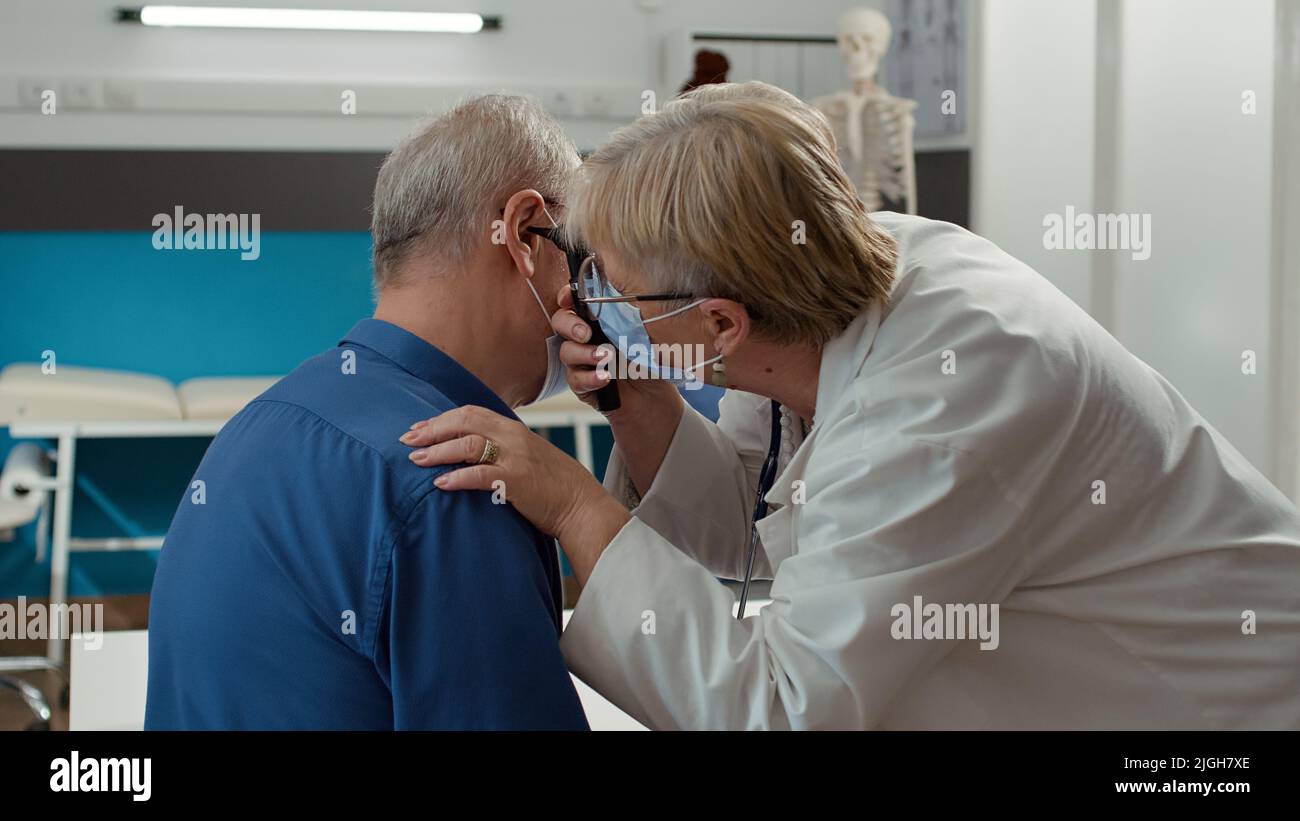 Medic using otoscope instrument to do ear examination, consulting old ...