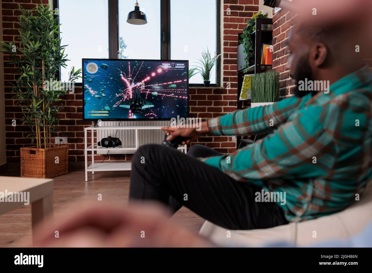 Cheerful man using joystick and console to play video games at home ...