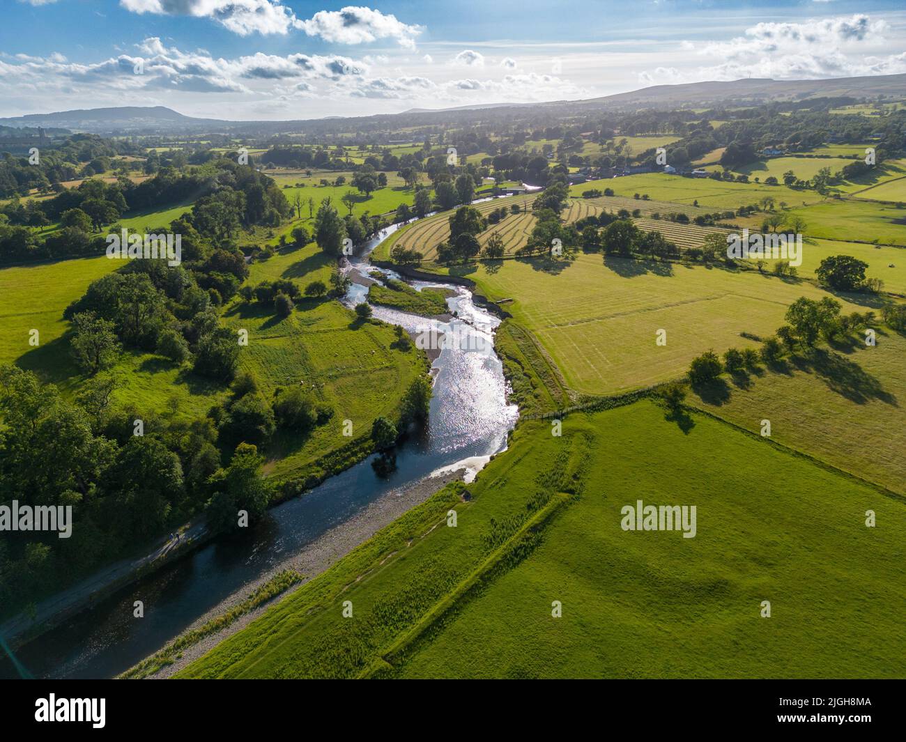 A bird's eye view of a river flowing through green cultivated fields in ...