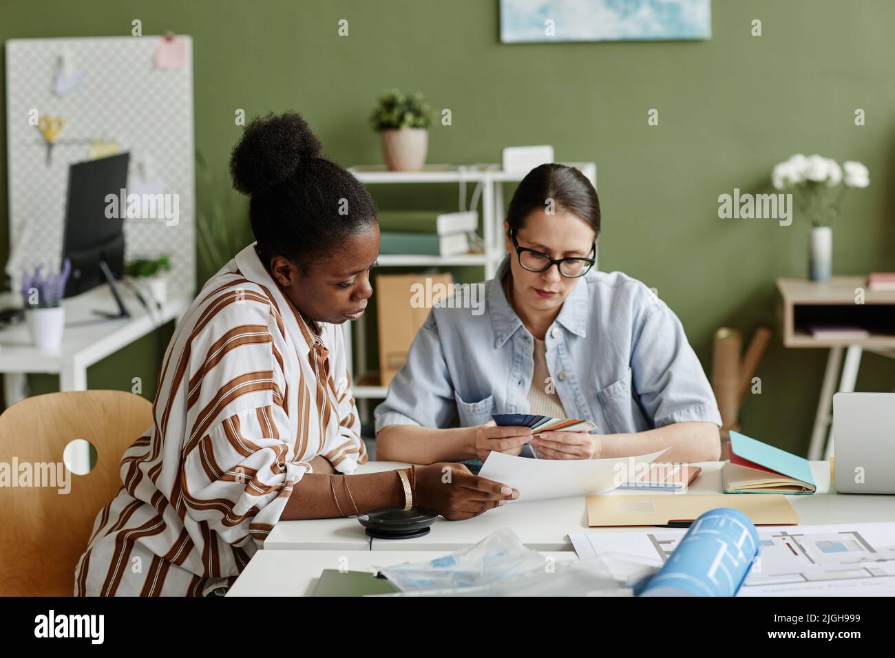 Multiethnic colleagues examining new project and choosing color in ...