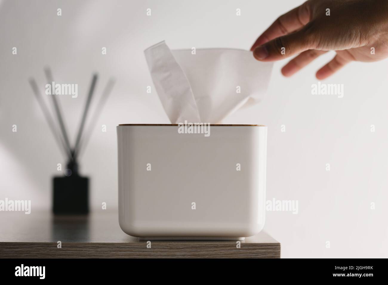 A hand pulling a tissue out of the white box Stock Photo - Alamy