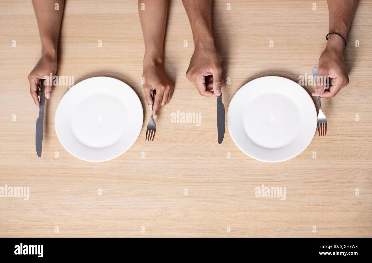 Hands of hungry millennial african american woman and man hold cutlery ...