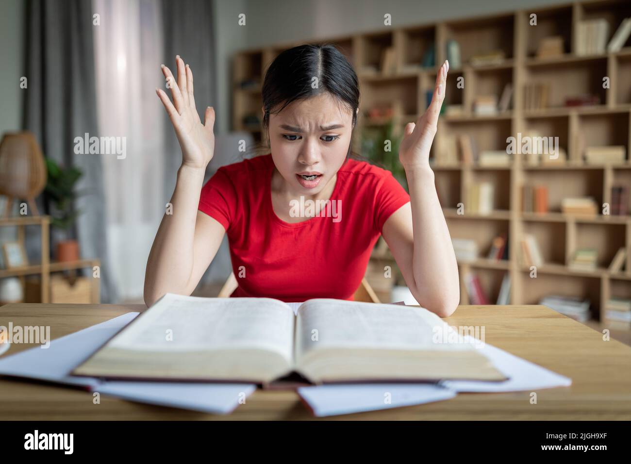 Big mistake. Amazed unhappy teenager chinese girl reading book ...