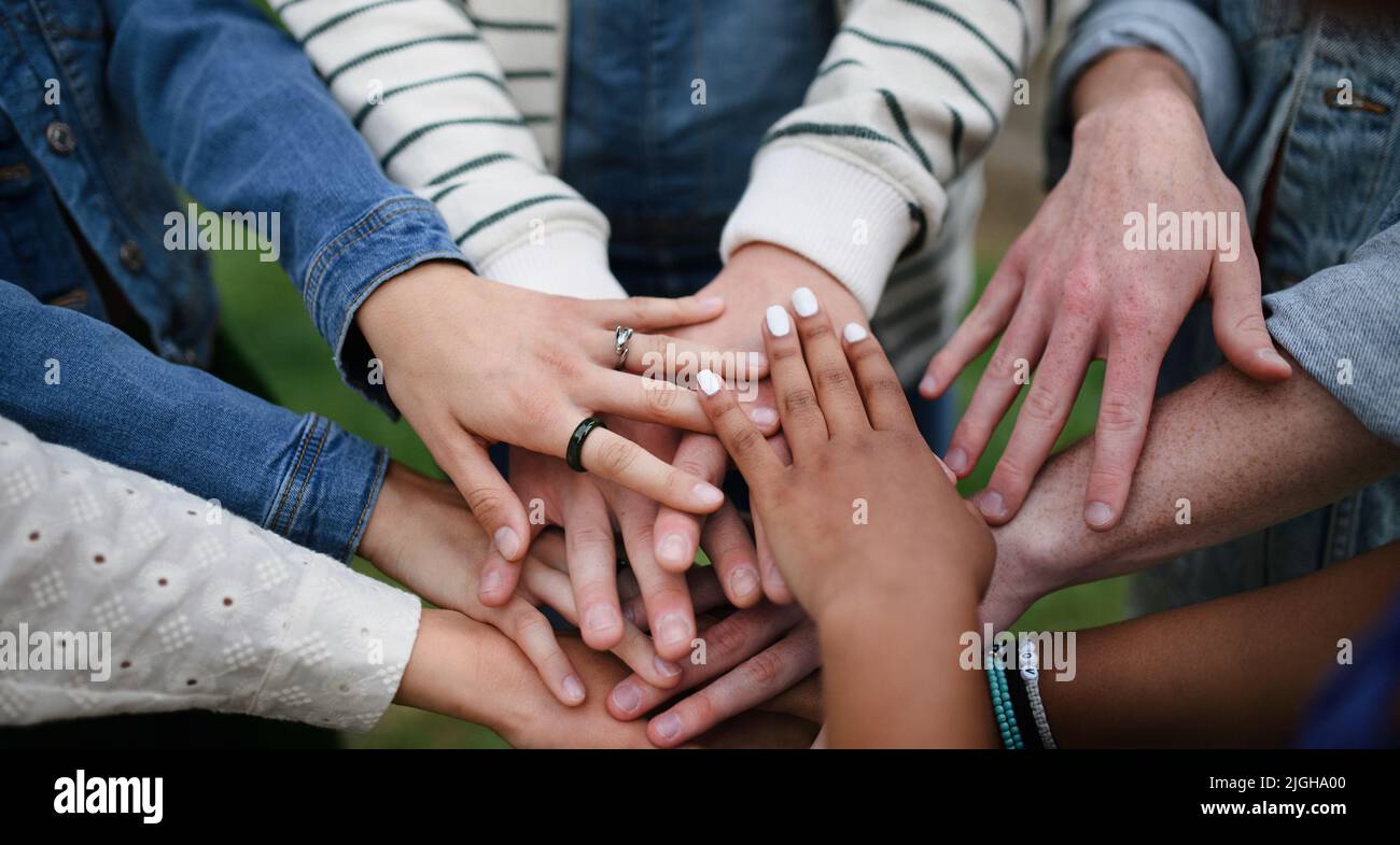 Close-up of diverse group of friends stacking their hands together in ...