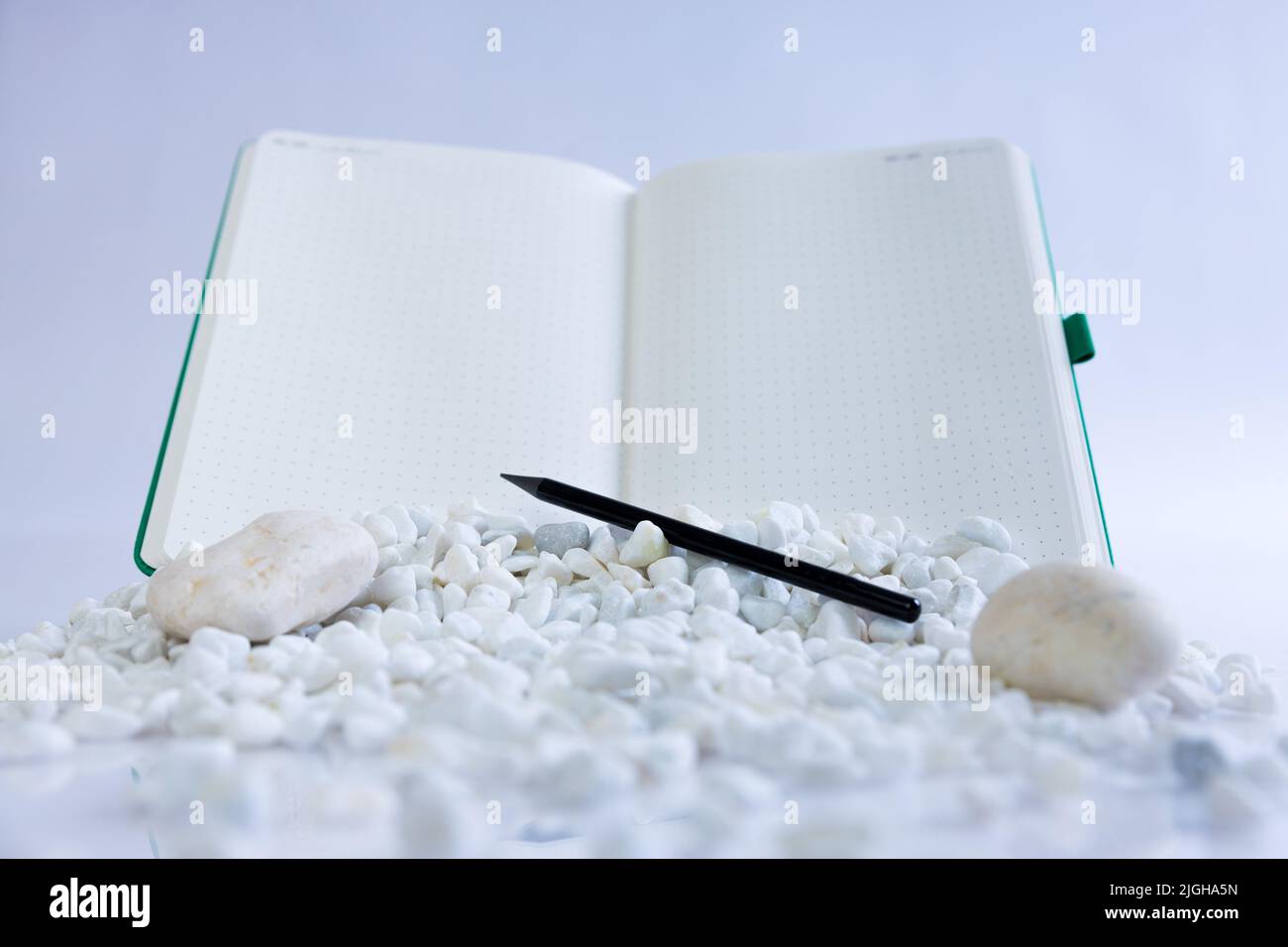 Notebook and pen on white studio background. White rocks falling in ...