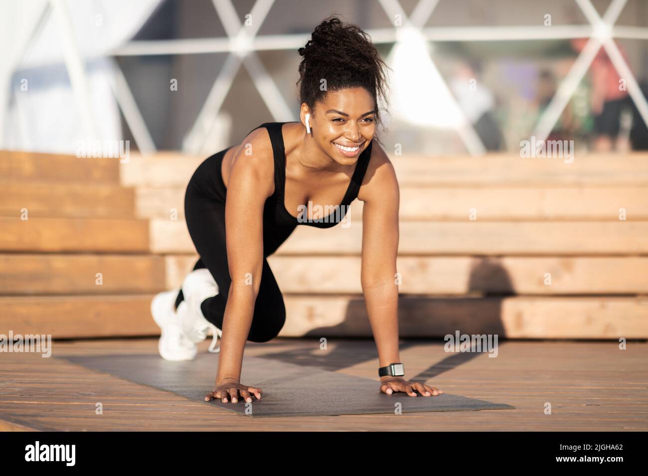 Positive well-fit black woman exercising outdoors, looking at copy ...