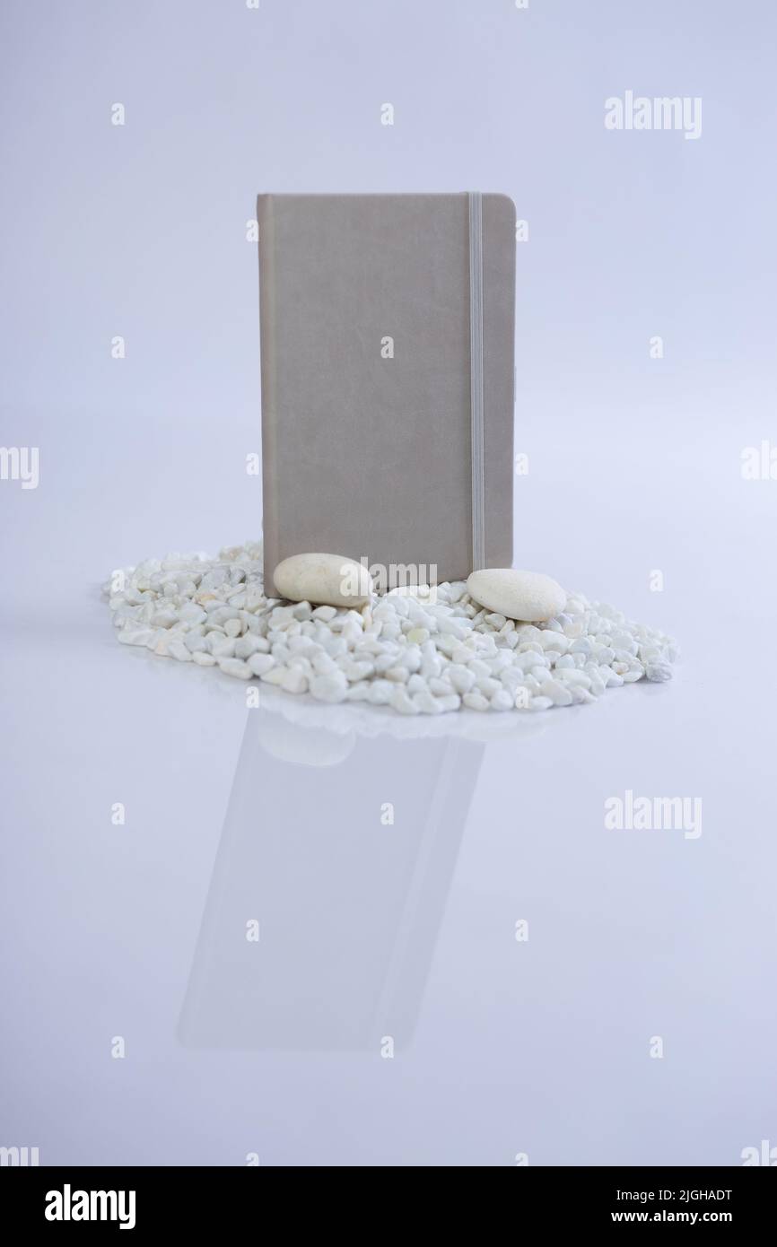 Grey notebook on a mountain stack of white rocks. Beautiful studio ...